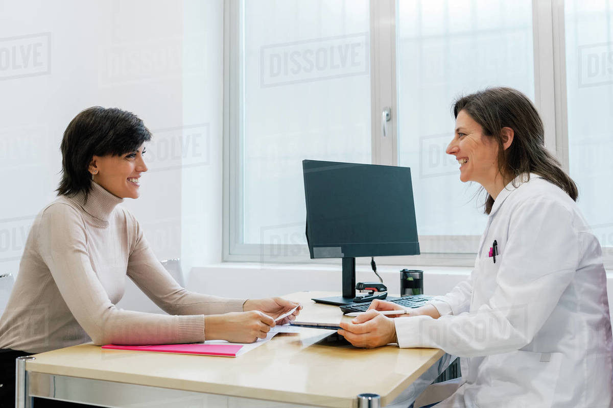 Side view of content female therapist in uniform interacting with ...