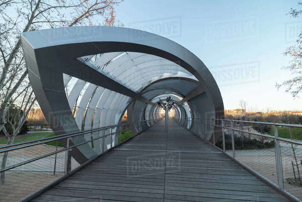 Perspective view of paved wooden bike path going to futuristic gallery ...