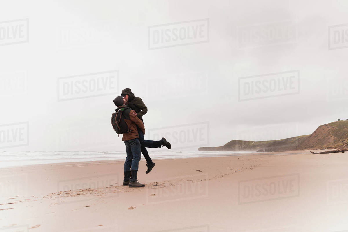 Side view of young man with backpack in warm wear holding on hands and ...