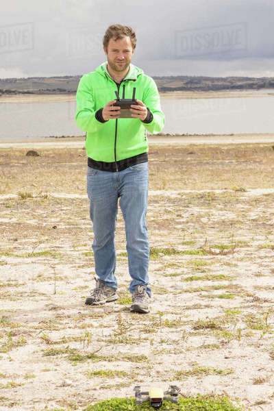 Immersed keen man lifting drone with camera from land using remote ...