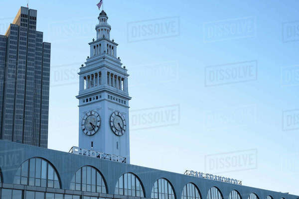 Tall clock tower with USA flag located near building of San Francisco ...