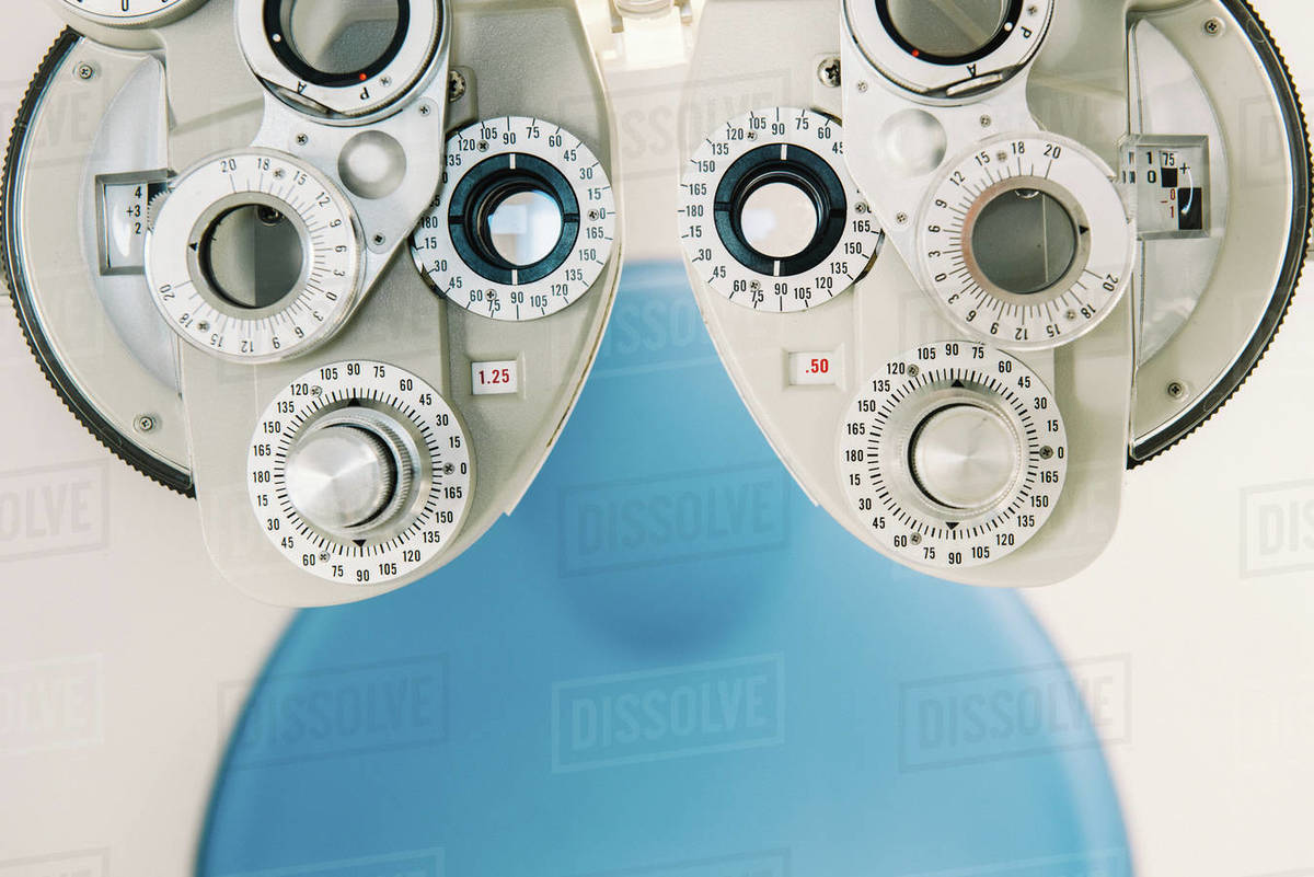 Modern vision test equipment and chair against white wall in optician ...