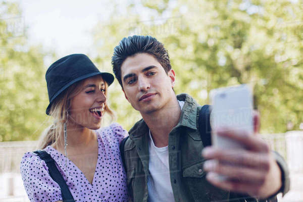 Young handsome man taking photo with girlfriend while walking in ...