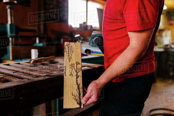 Side view of crop male pyrographer standing in workshop and ...