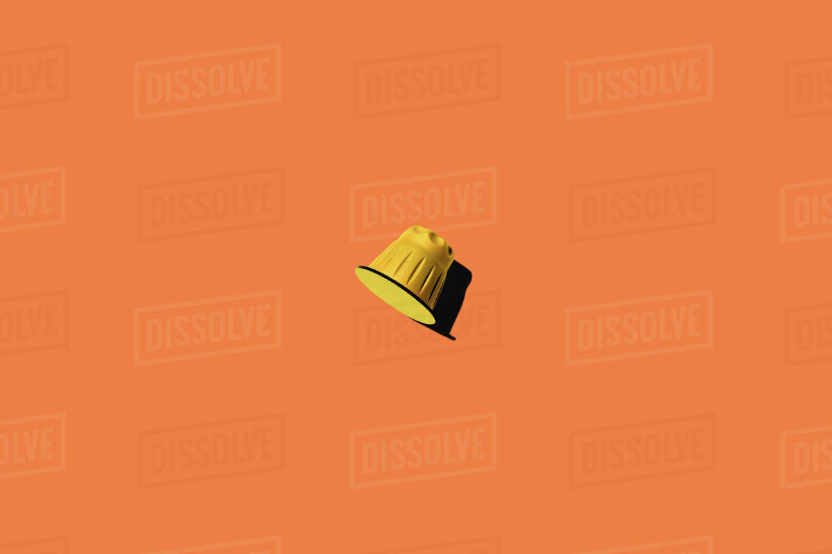 Top view of yellow coffee pod placed on orange background - Royalty ...