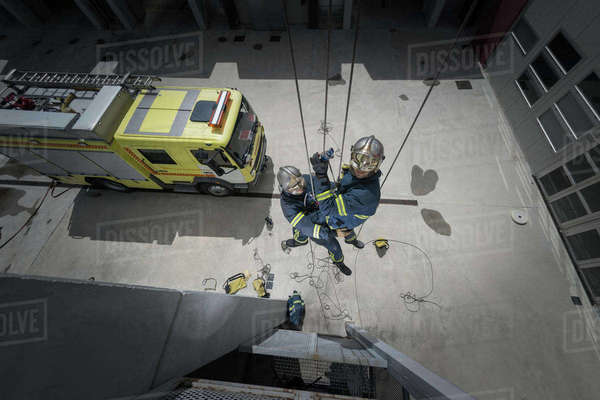 From above of firefighters in protective equipment climbing ropes near ...