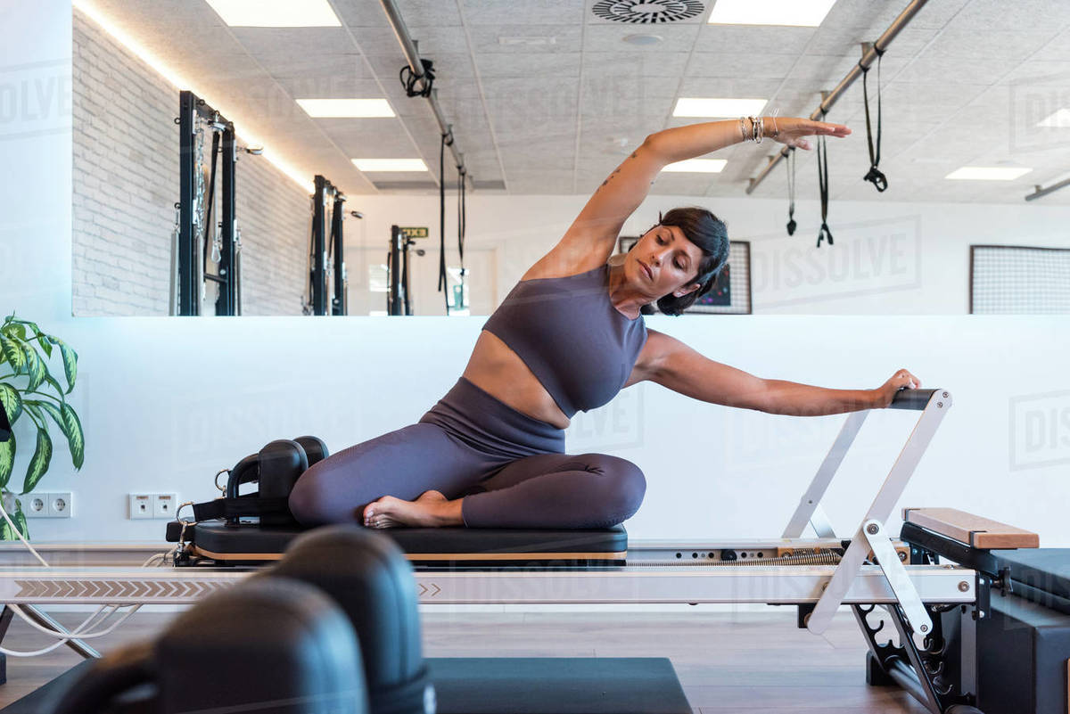 Slim adult female doing Seated Side Bend and stretching body on modern ...