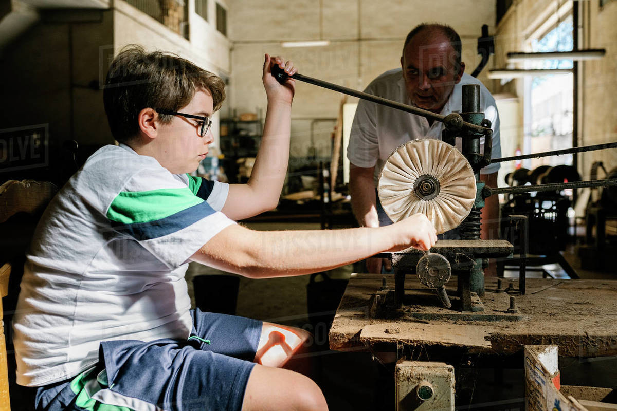 Focused teenage boy working with old drill press under supervision of ...