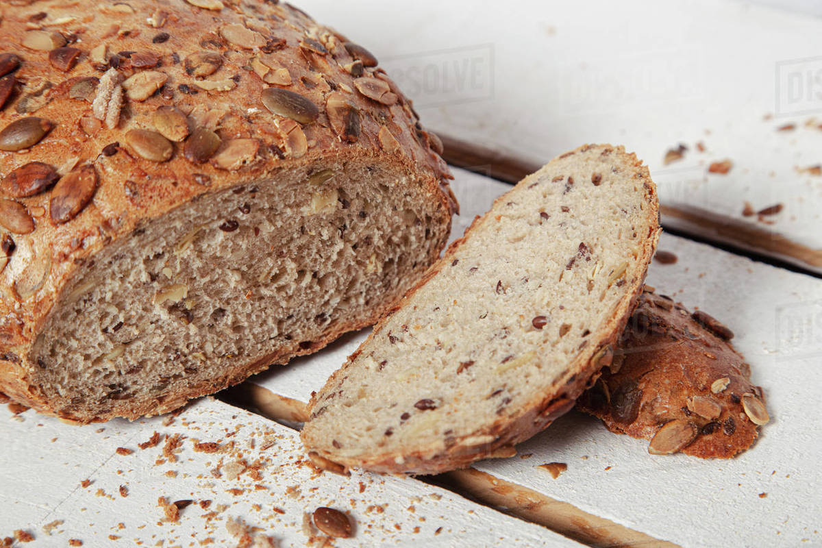 From above round rye bread loaf with few cut slices on wooden table ...