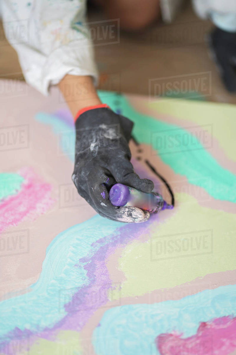 Crop anonymous female illustrator in dirty robe and gloves sitting on ...