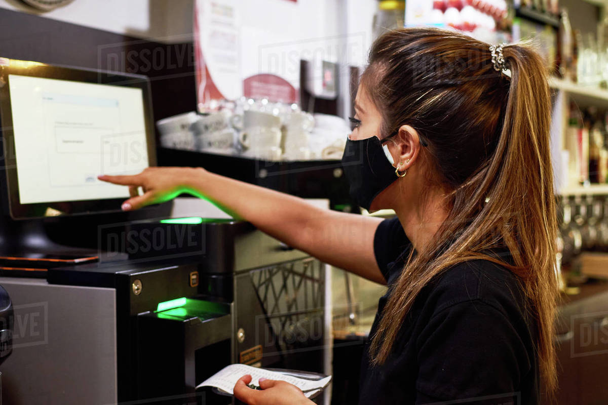 Side view of female waiter making order on touch screen computer during ...