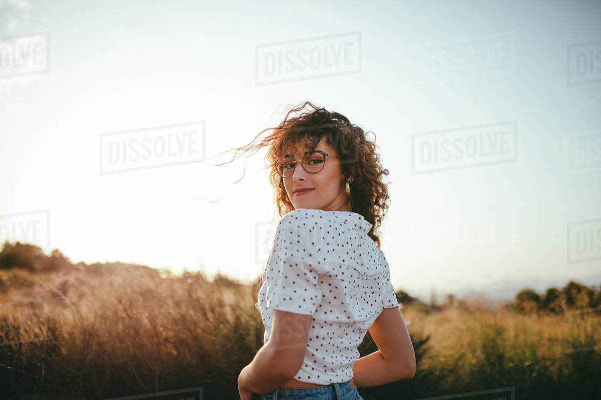 Fit charming woman in eyeglasses and casual clothes looking back at ...