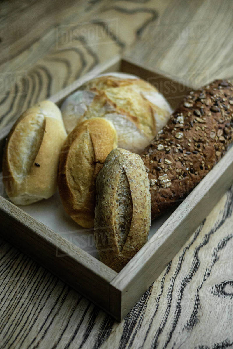 From above loaves of fresh bread placed in wooden box on table in ...