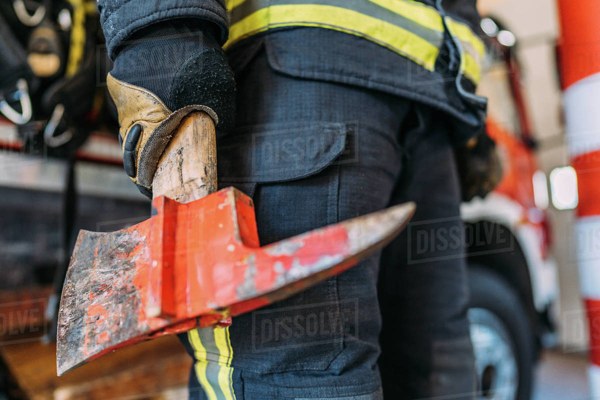 Side view of unrecognizable firefighter in uniform and hardhat carrying ...