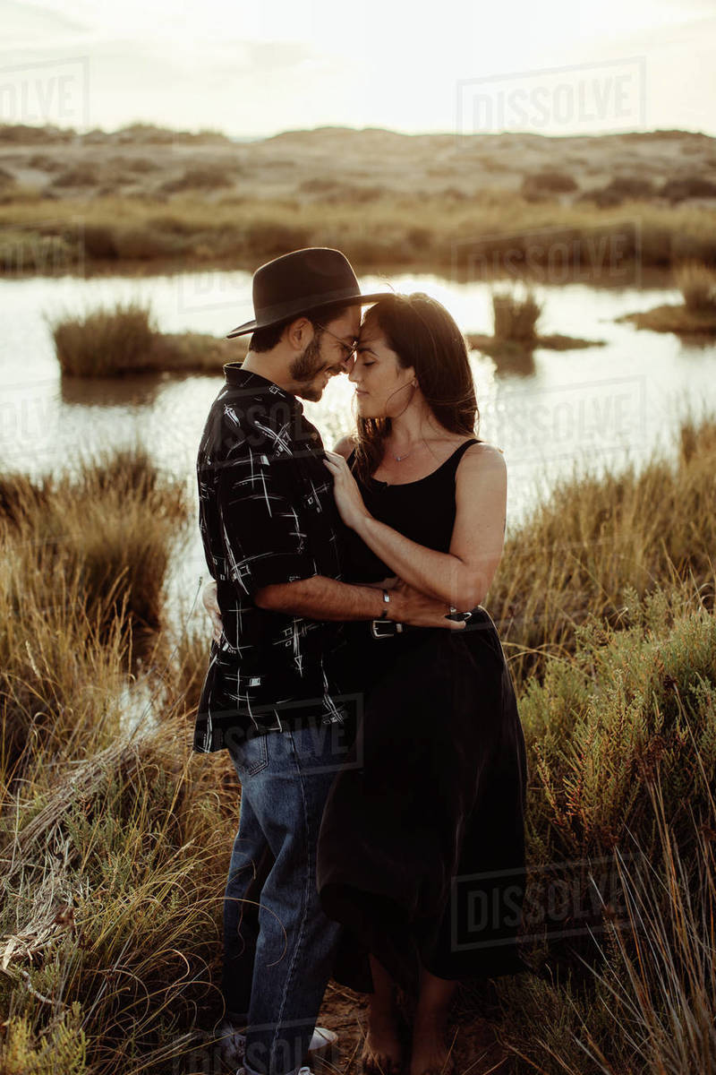 Full body side view of young loving couple in casual clothing cuddling ...
