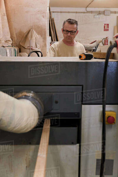 Attentive middle aged workman in glasses and casual clothes focusing ...