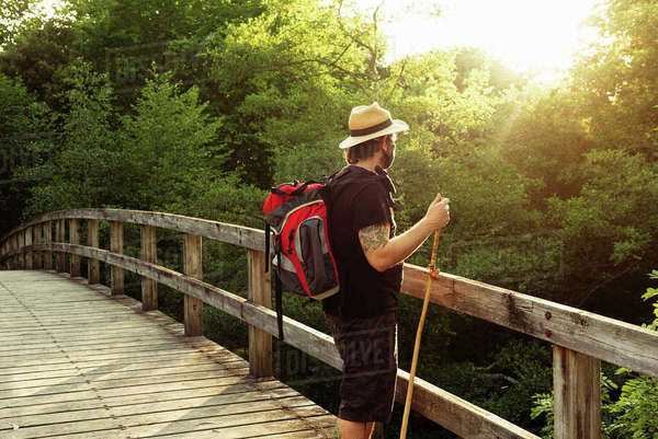 Side view of unrecognizable male wanderer with backpack and wooden ...