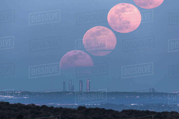 Large red moons shining on blue night sky over skyscrapers of modern ...