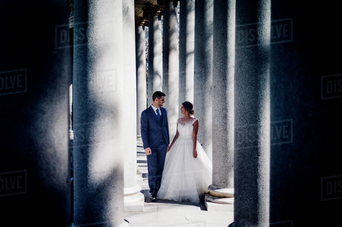 From below side view of young elegant couple in wedding dresses walking ...