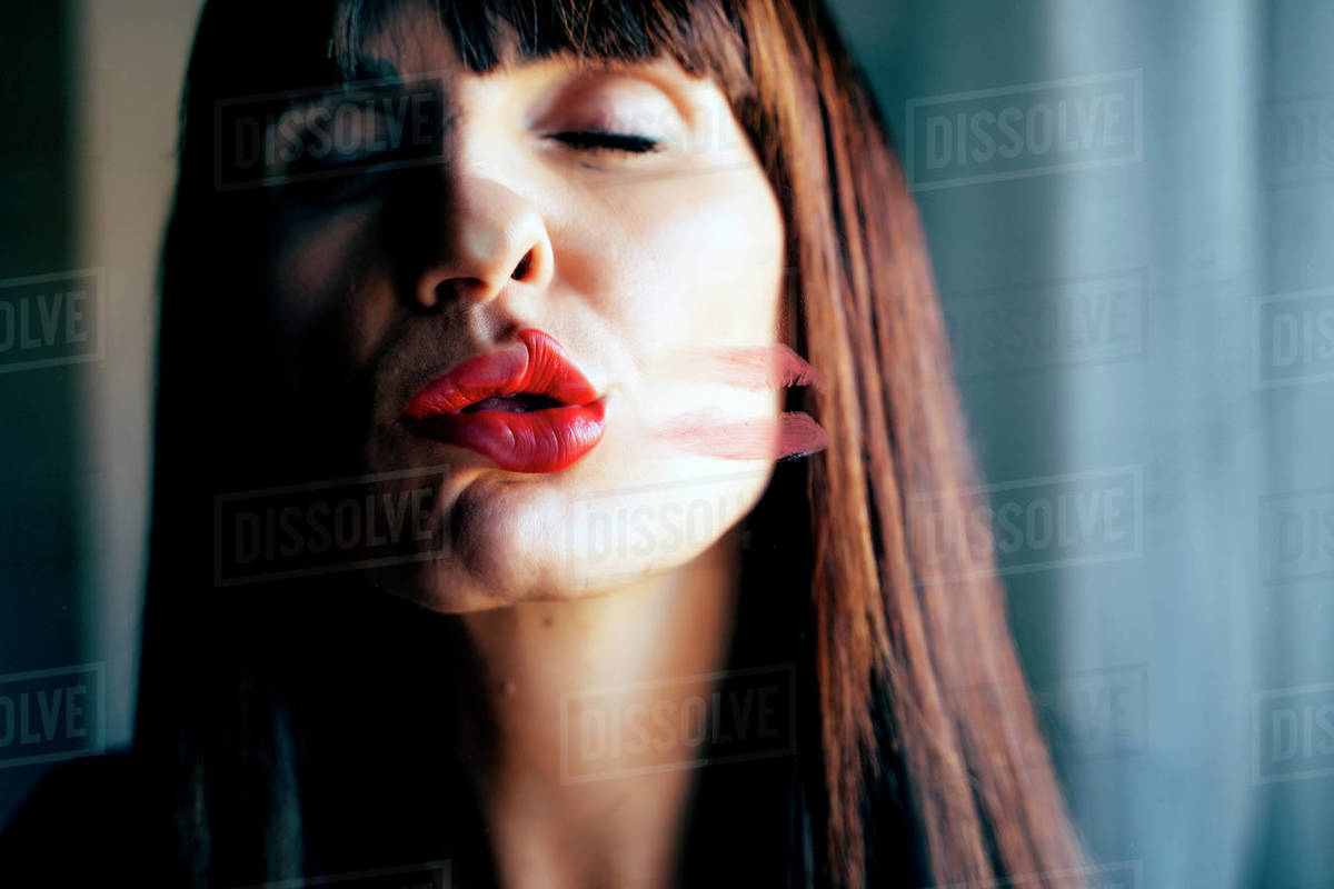 Attractive female with red lips kissing clean transparent glass ...