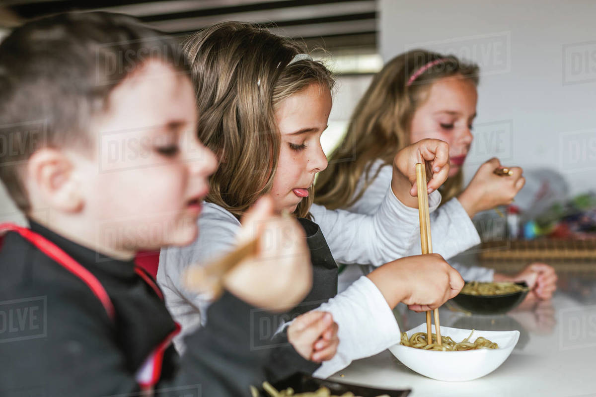 Boy and two girls eating tasty noodles with vegetarian cutlets and ...