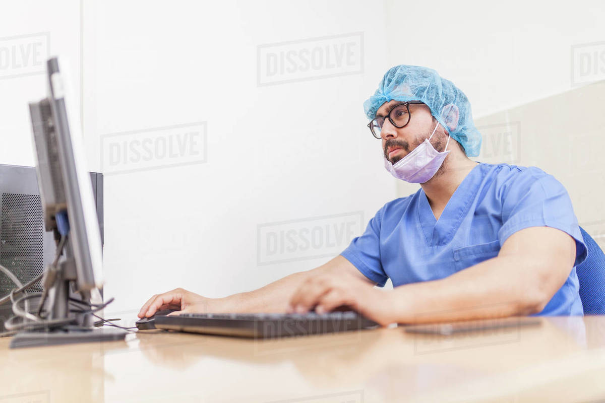 male surgeon using her computer in her office before the surgery ...