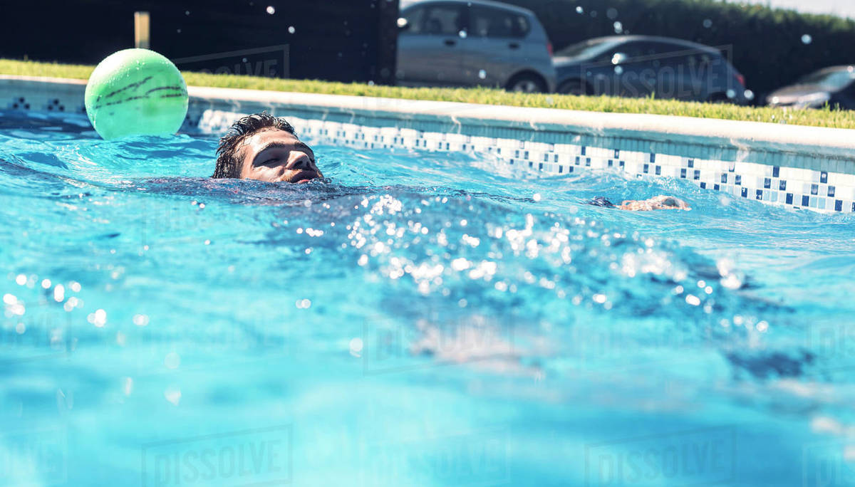 Man floating in swimming pool - Stock Photo - Dissolve