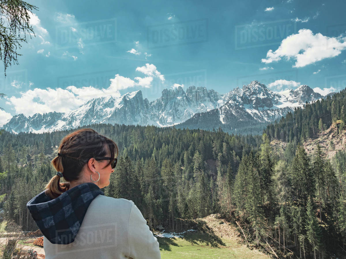 Back view of young woman in sweater protecting face from sun by hand ...