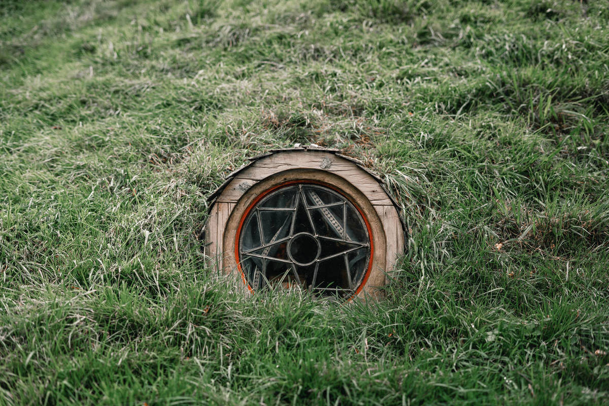Ornamental round window of hobbit burrow on grassy hillside in Mount ...