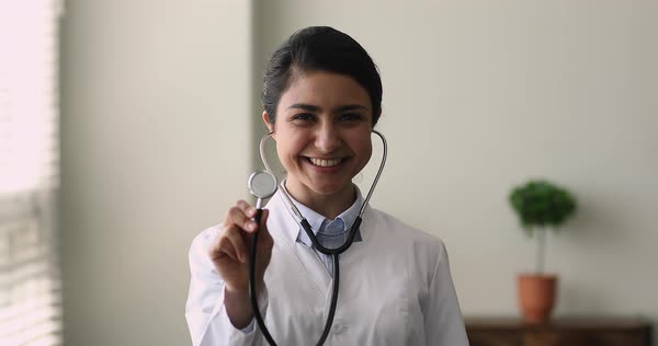 Head shot portrait smiling Indian female doctor holding stethoscope ...