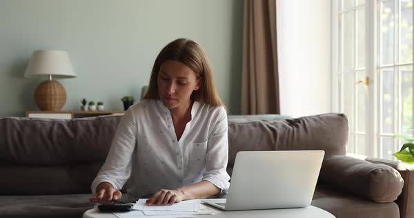 Nervous confused young woman calculate payments for bills having ...