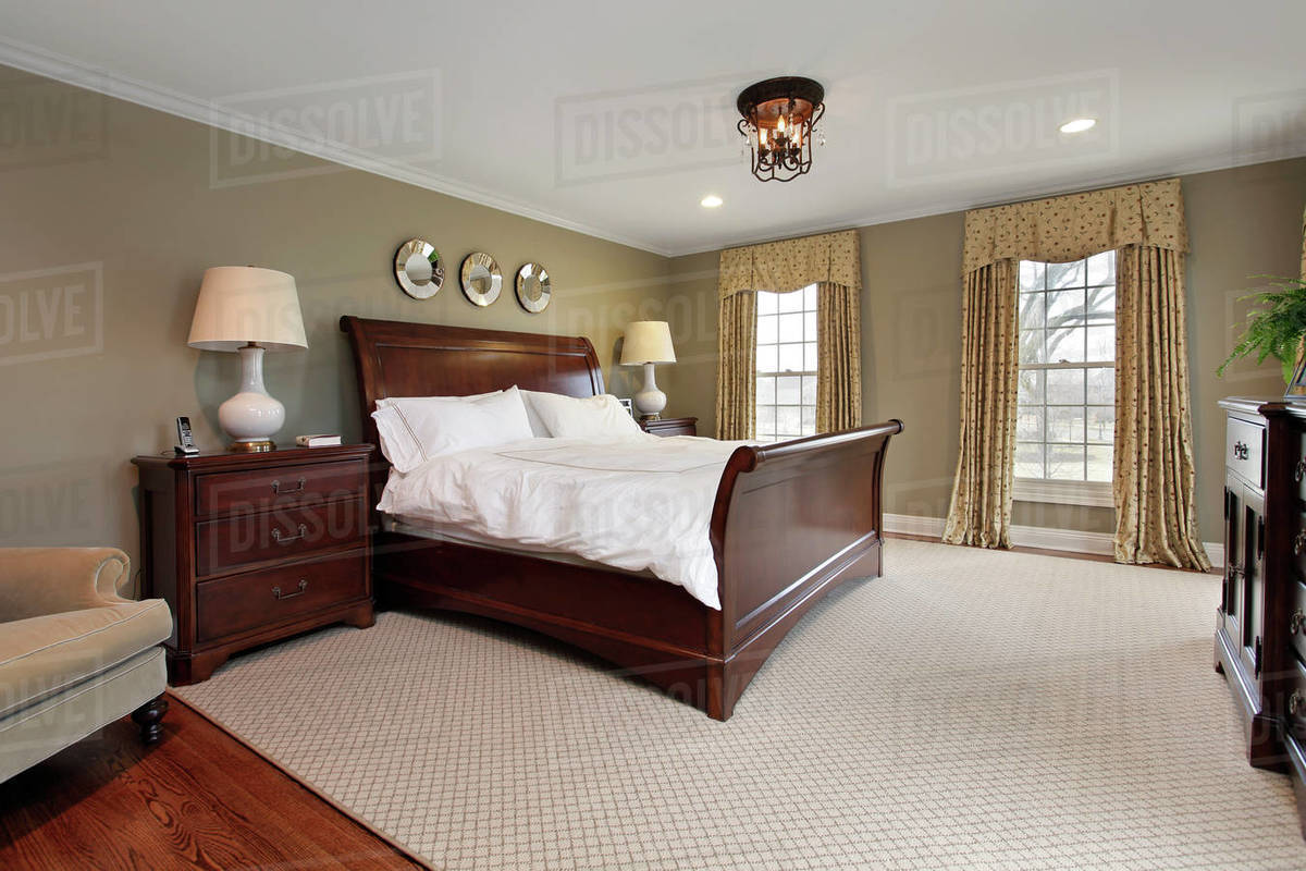 Master bedroom in luxury home with dark wood bed frame - Royalty-free ...
