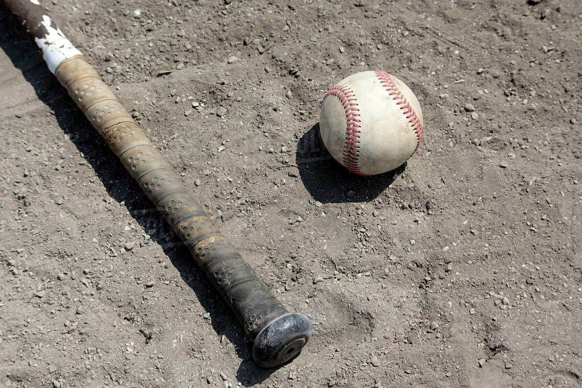 Close up of a baseball and bat in dirt - Stock Photo - Dissolve