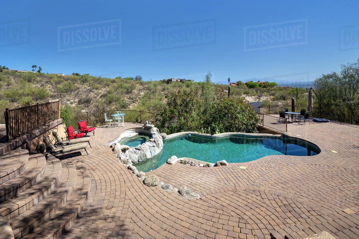Swimming pool and terraced patio at a luxury home in a desert ...