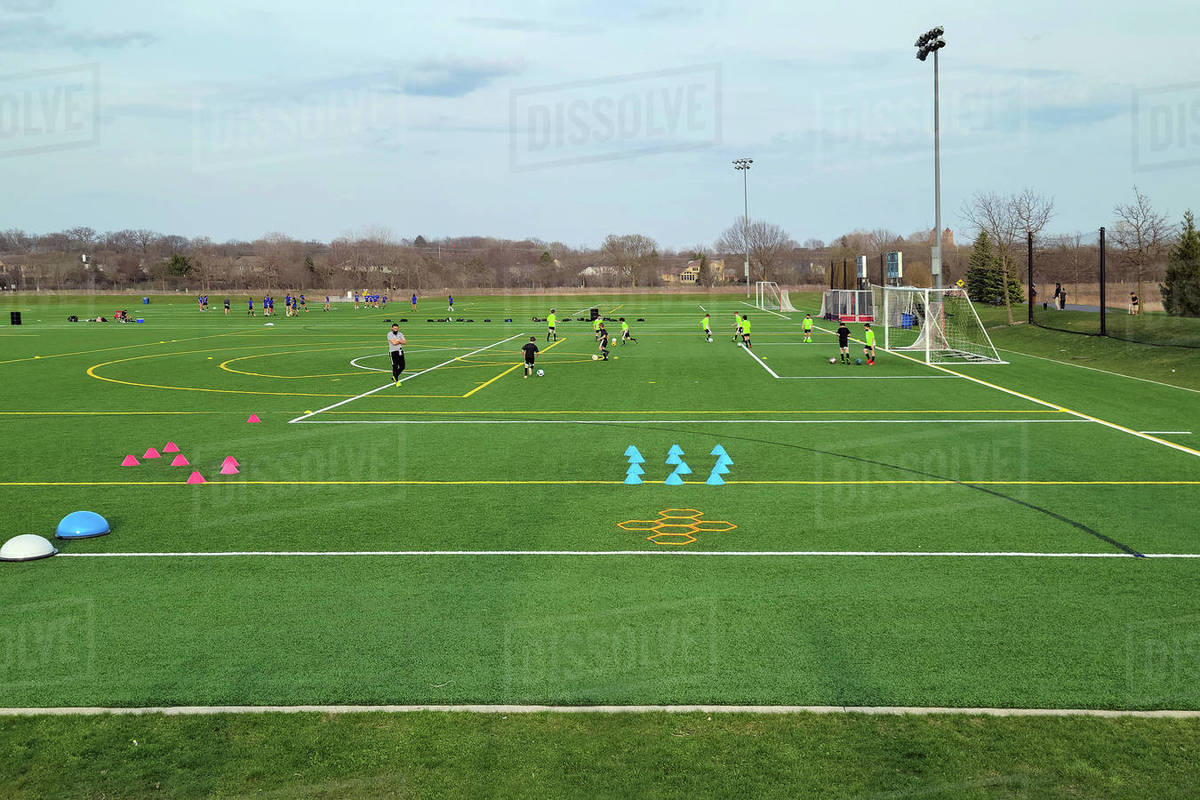 Boys practicing soccer on a multi-use ball field in early spring at a ...
