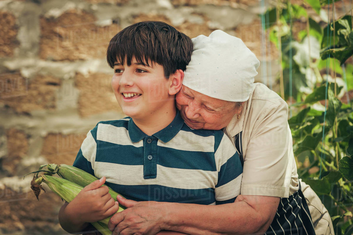 Grandmother hugs her grandson who is holding a corn crop. Color graded ...