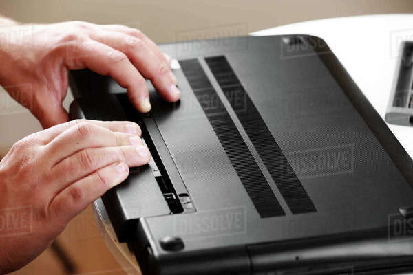 Repairman's hands removing the power battery from the laptop. Computer ...