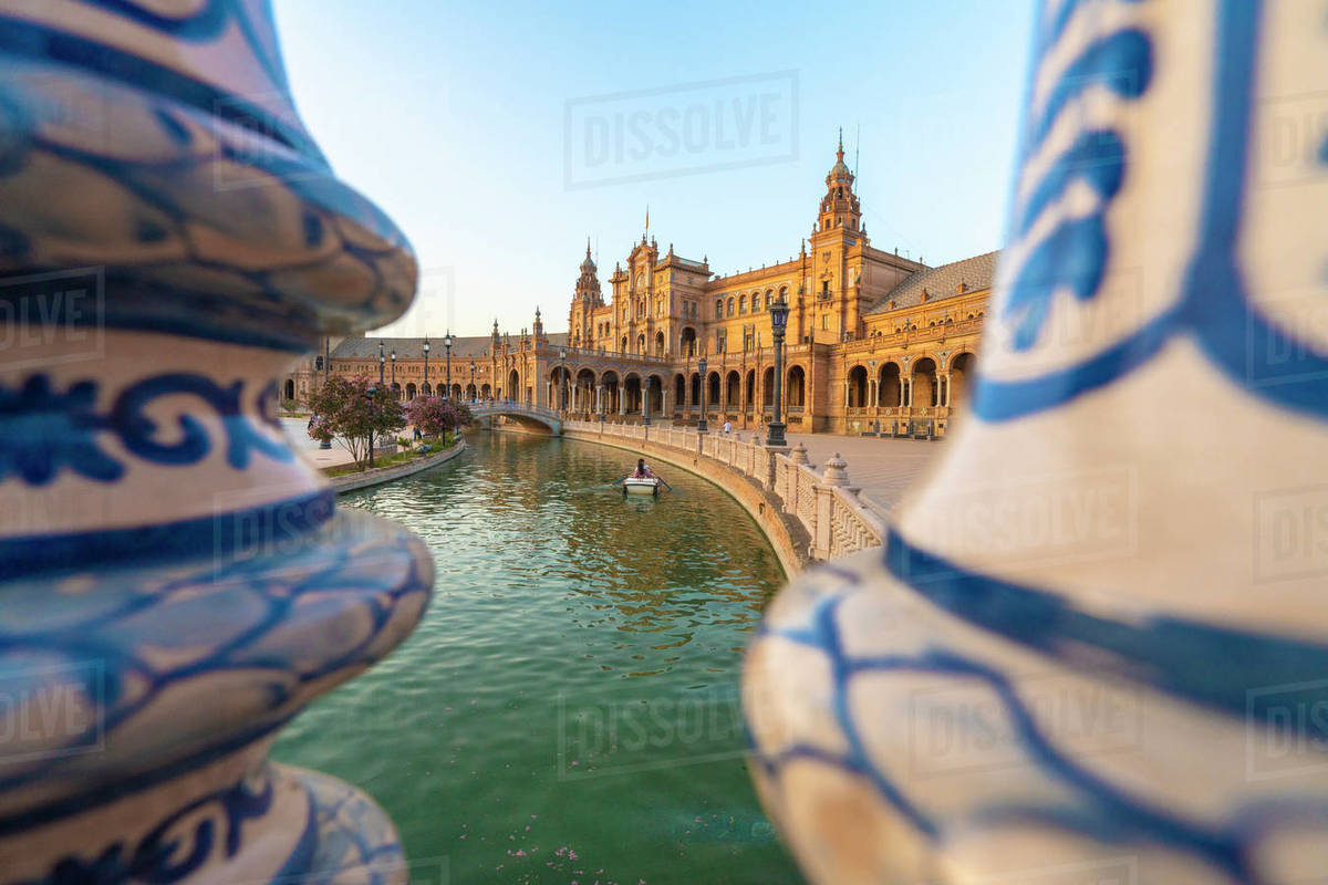 Rowing boat along the canal seen from the ceramic decorated pillars of ...