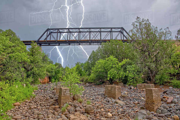 Lightning from a monsoon storm striking behind an old railroad trestle ...