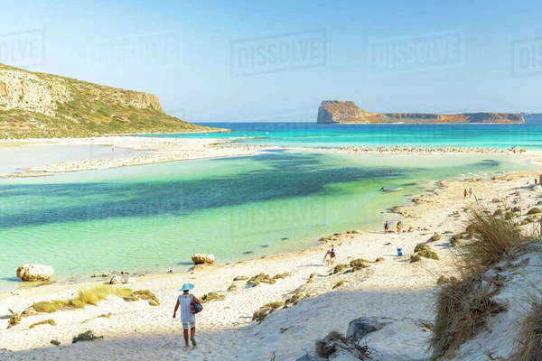 Tourists walking to the white sand beach surrounding Balos lagoon ...