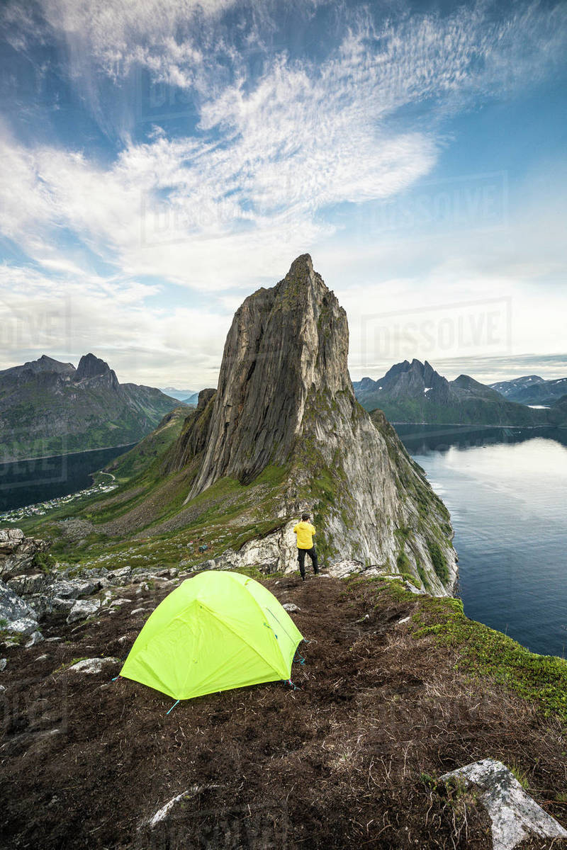 Hiker man with camping tent admiring Mount Segla and fjord from Hesten ...