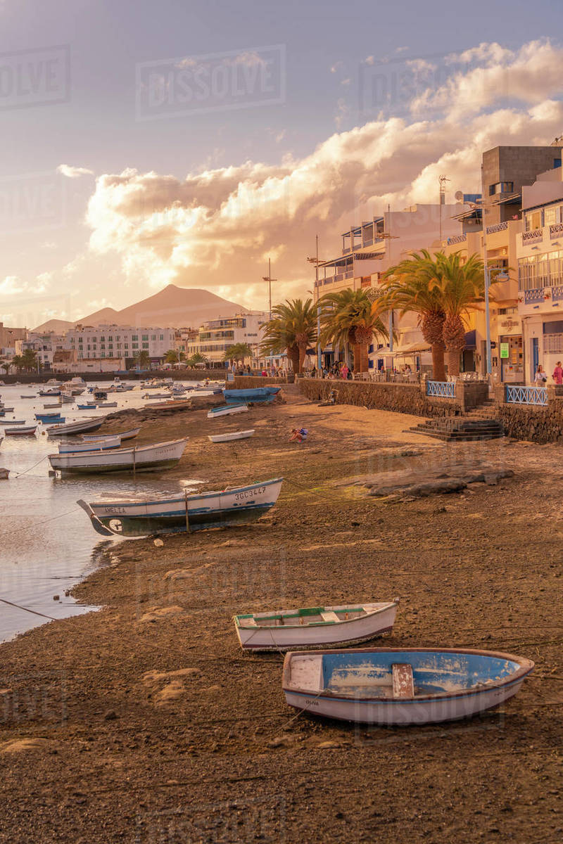 View of boats on beach in Baha de Arrecife Marina surrounded by shops ...