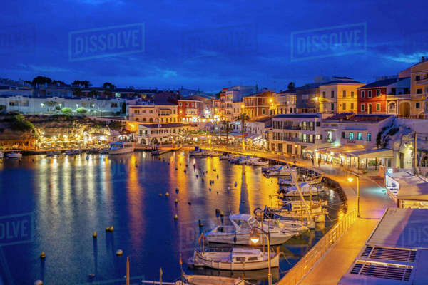 View of cafes, restaurants and boats in harbour at dusk, Cales Fonts ...