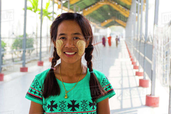 Young Burmese woman with leaves painted on her cheeks with thanaka ...