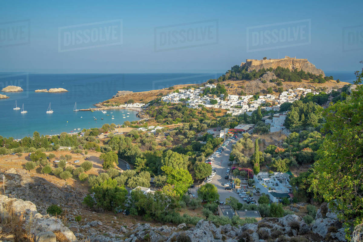 View of sailboats in the bay, Lindos and Lindos Acropolis from elevated ...