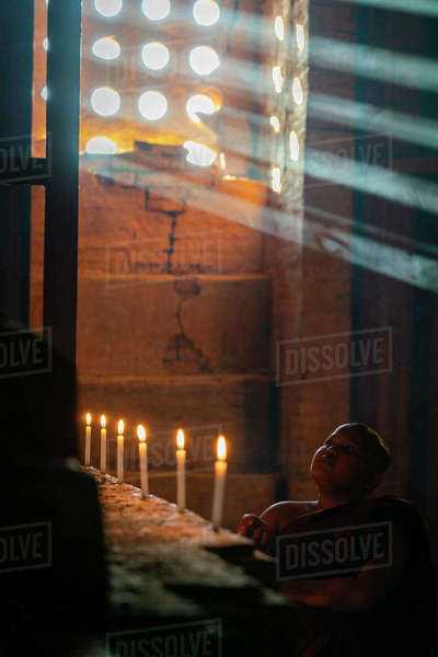 Novice monk inside temple looking up to Buddhist statue, Bagan (Pagan ...