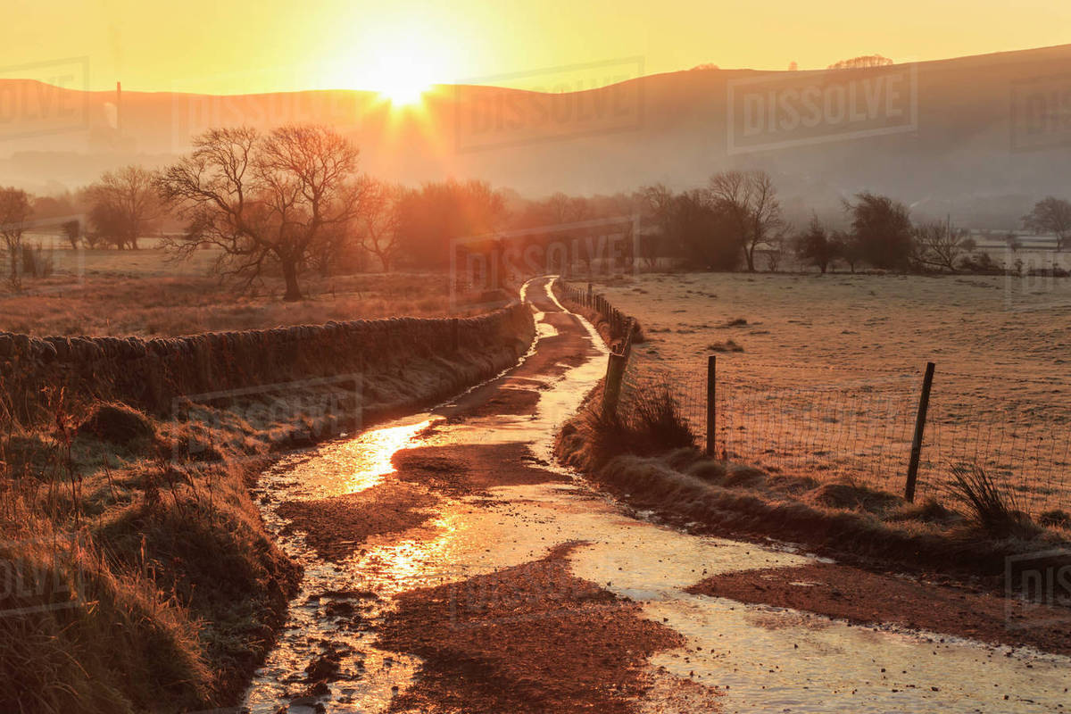 Misty and frosty sunrise over a country lane in winter, Castleton, Peak ...