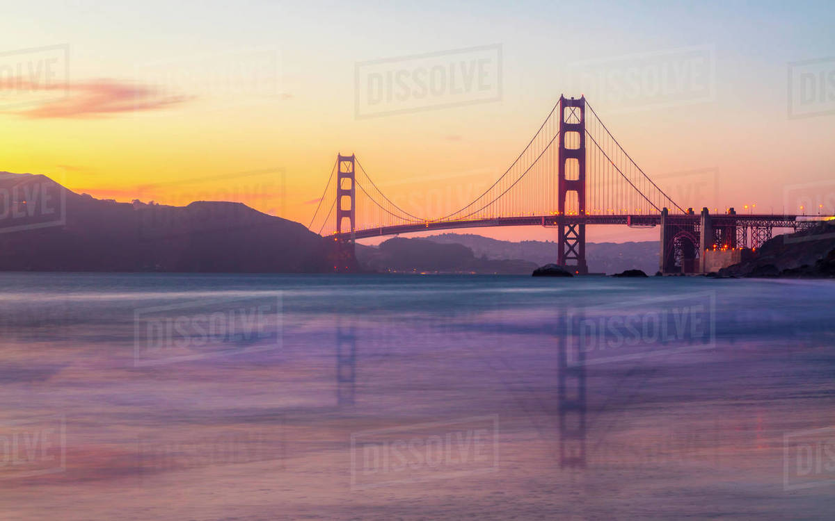 Soft flowing water reflects the beautiful Golden Gate Bridge at sunset ...