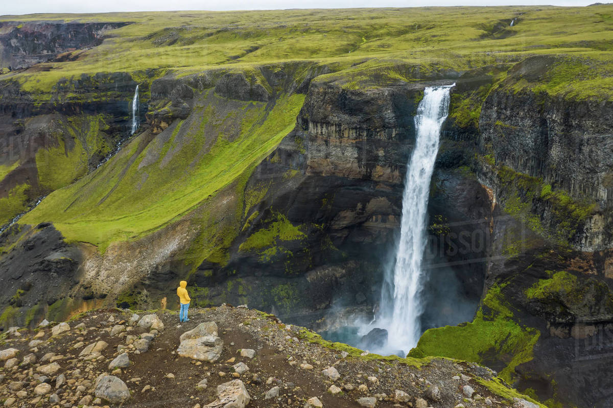 Aerial view of man standing on the cliff edge enjoying Iceland highland ...