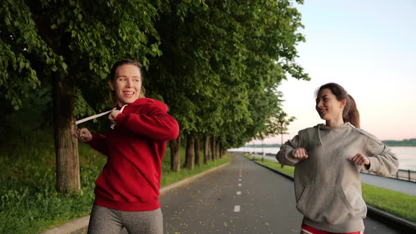 Two happy young girls are talking to each other and doing muscle ...